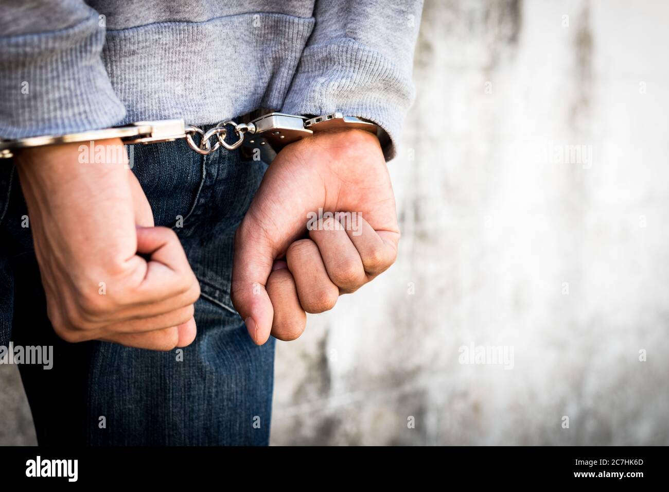 Close up hands tied up handcuffs in behind his body. Arrested man ...