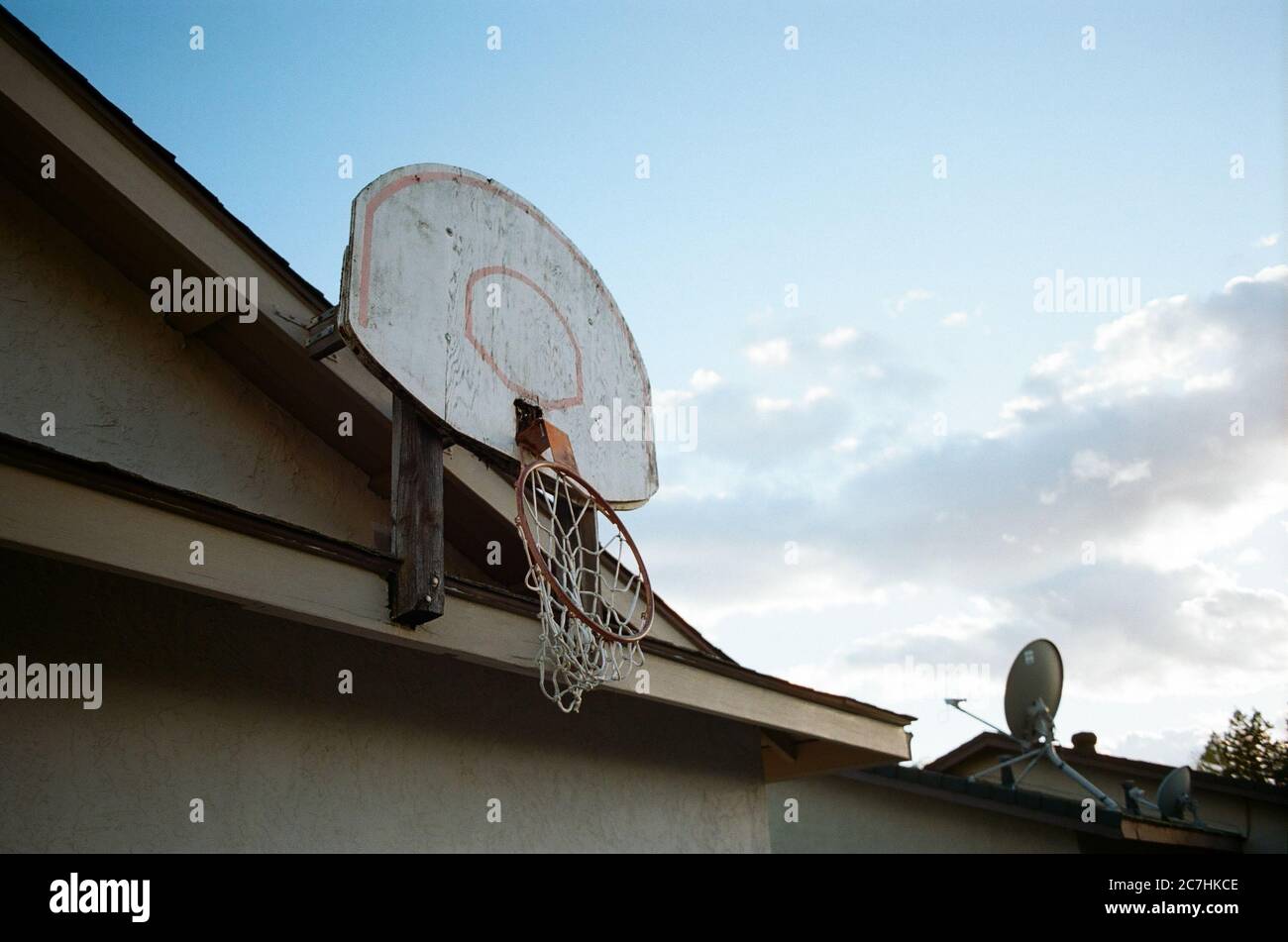 Low angle shot of a broken basketball basket on the top of a house ...