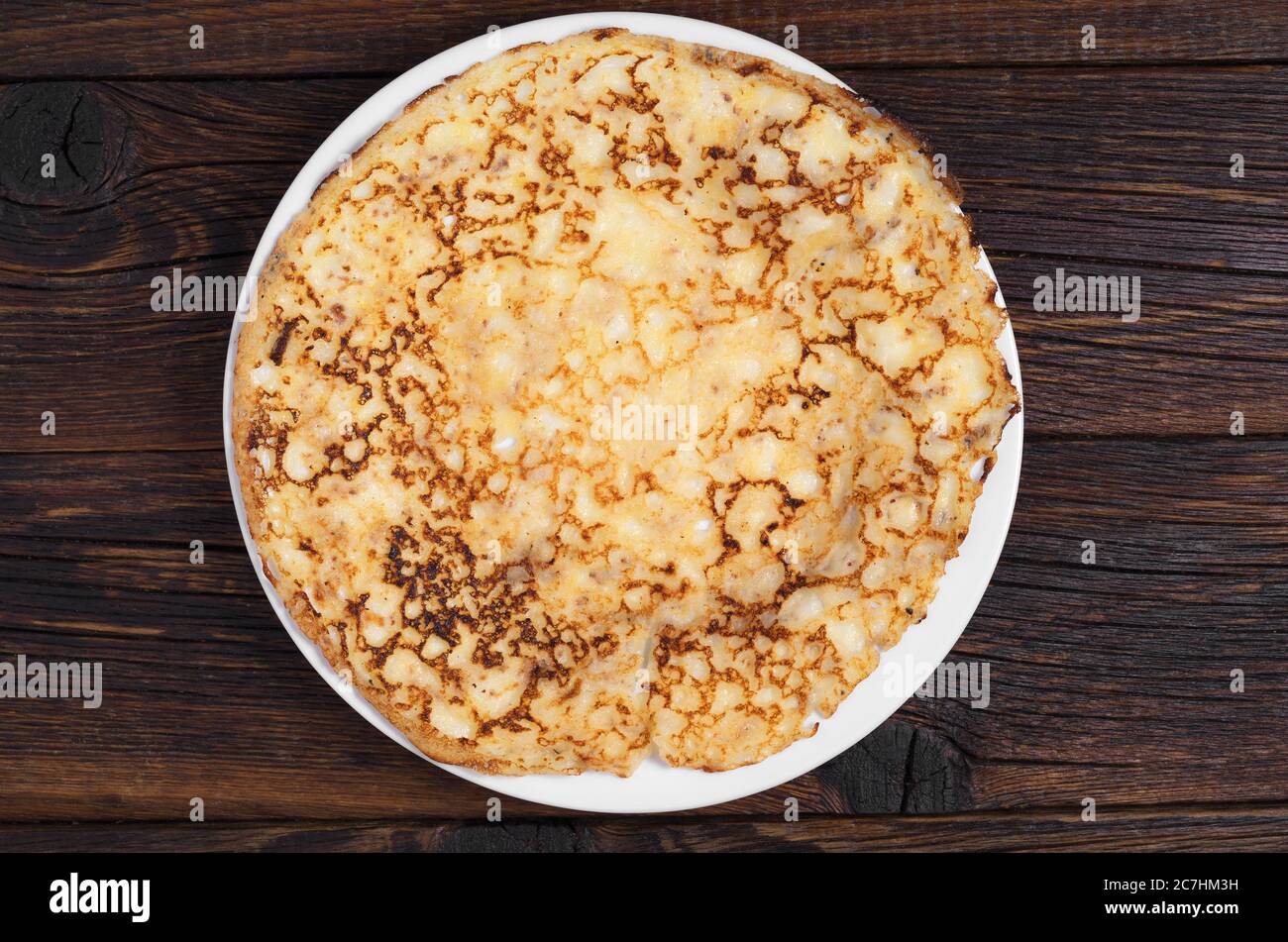 One fried pancake in plate on dark wooden table, top view Stock Photo ...