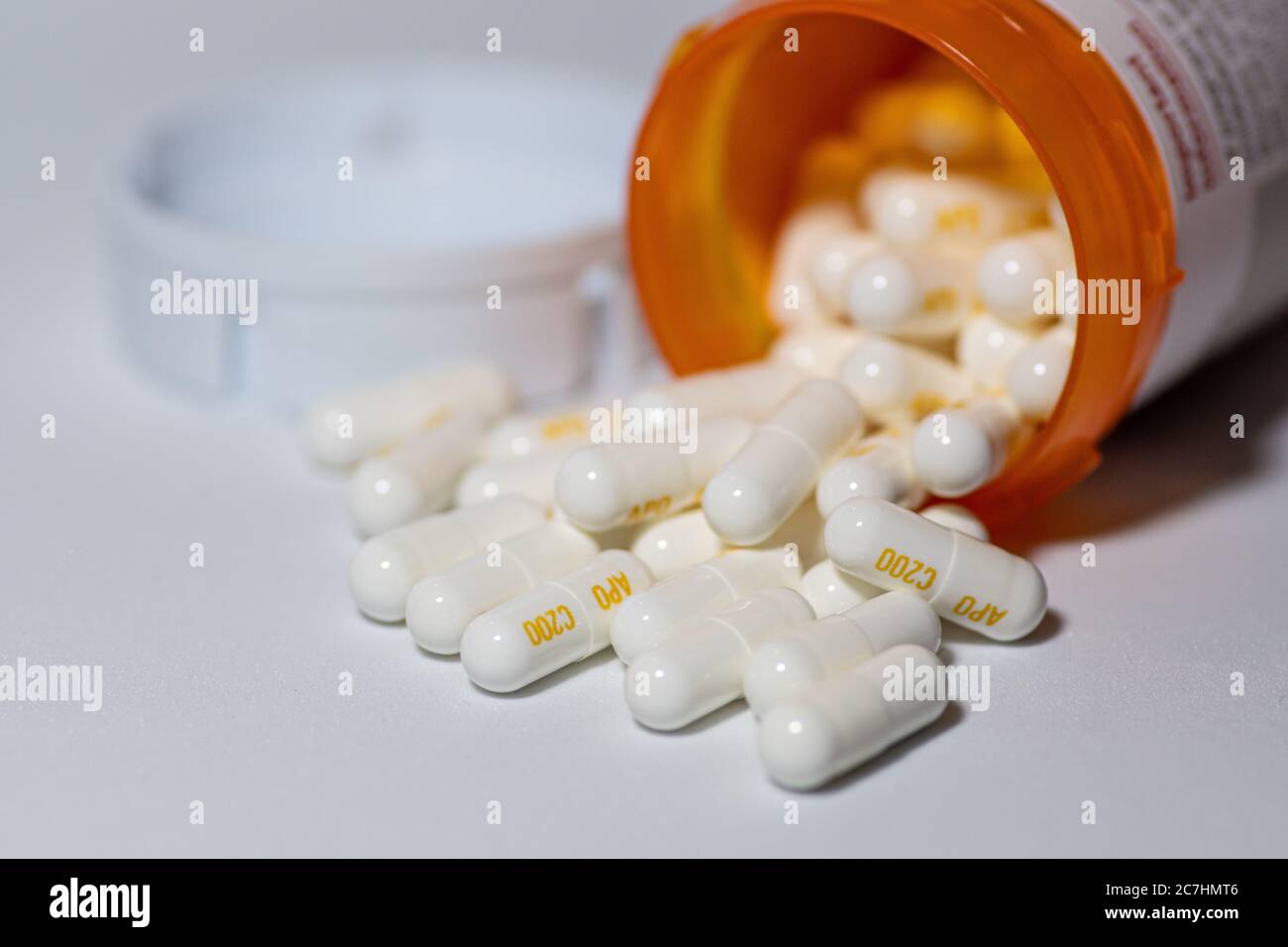 Closeup shot of white capsules pouring out of the bottle on a white ...