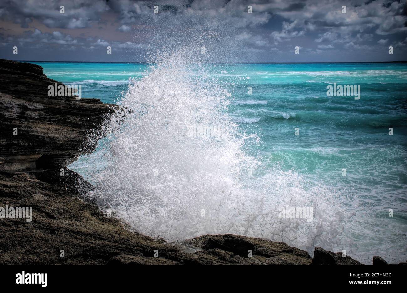 Crashing wave hits rocks on beach on Horseshoe Bay Beach, Bermuda Stock ...