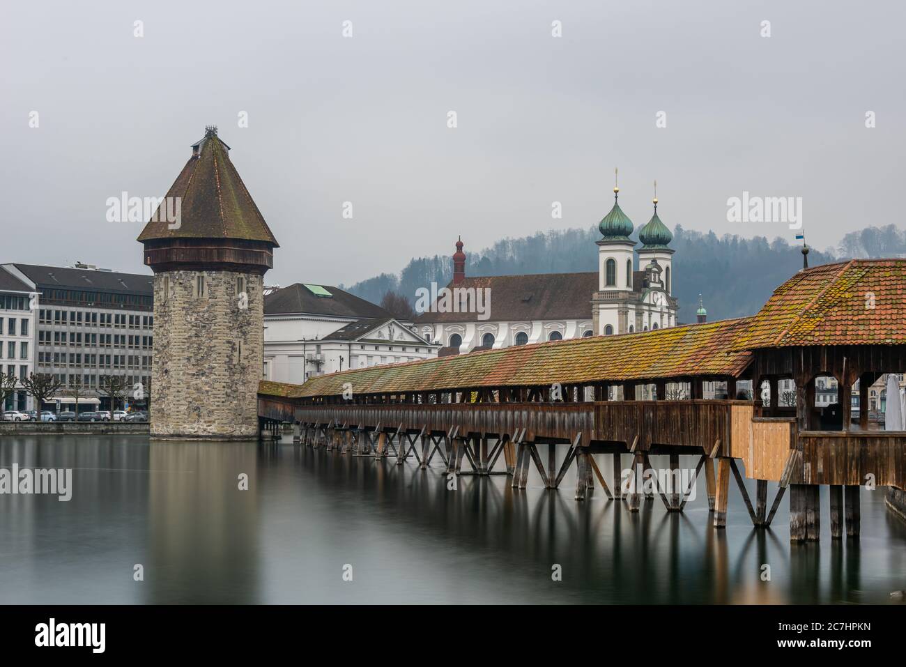Lucerne Jesuit Church surrounded by water under a cloudy sky in Lucerne ...