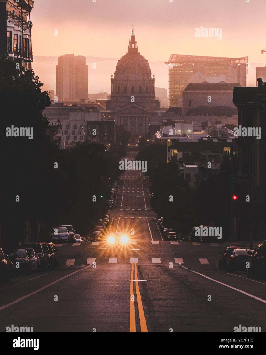 Vertical shot of cars driving up the road in the middle of buildings ...