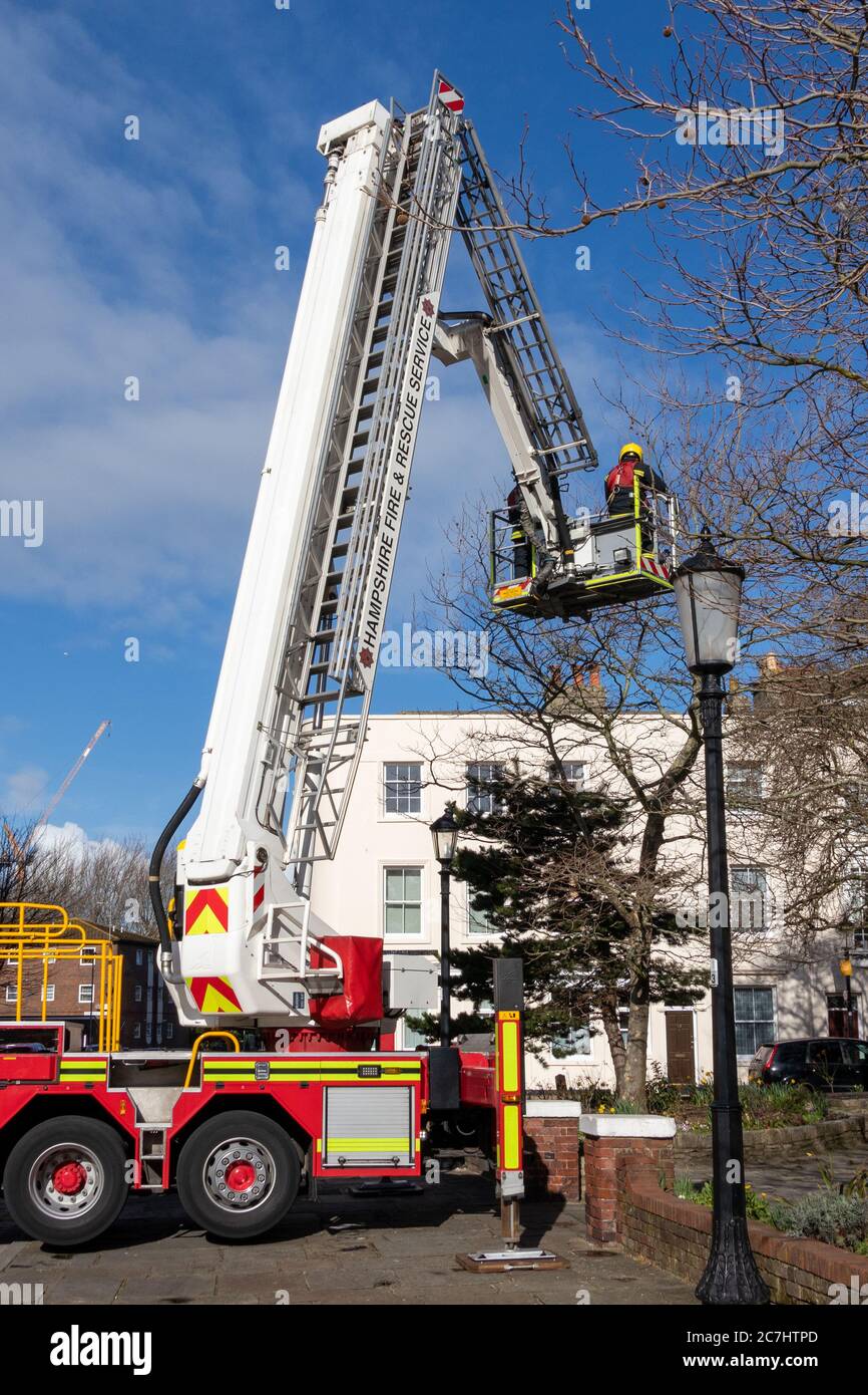 Firefighters in a tall crane being lifted up to a building with fireman ...