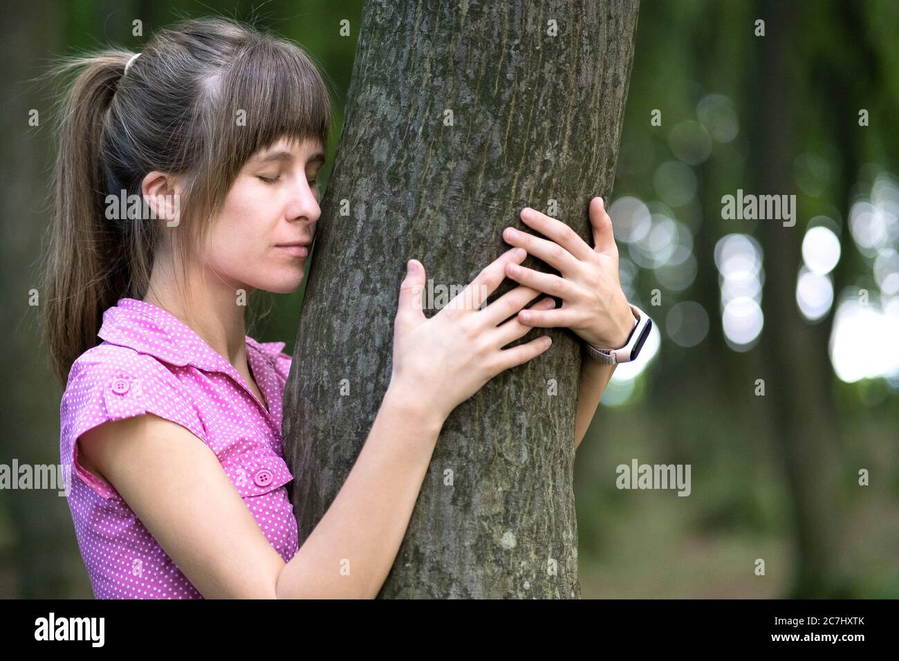 Young happy woman hugging big tree trunk in summer park Stock Photo - Alamy