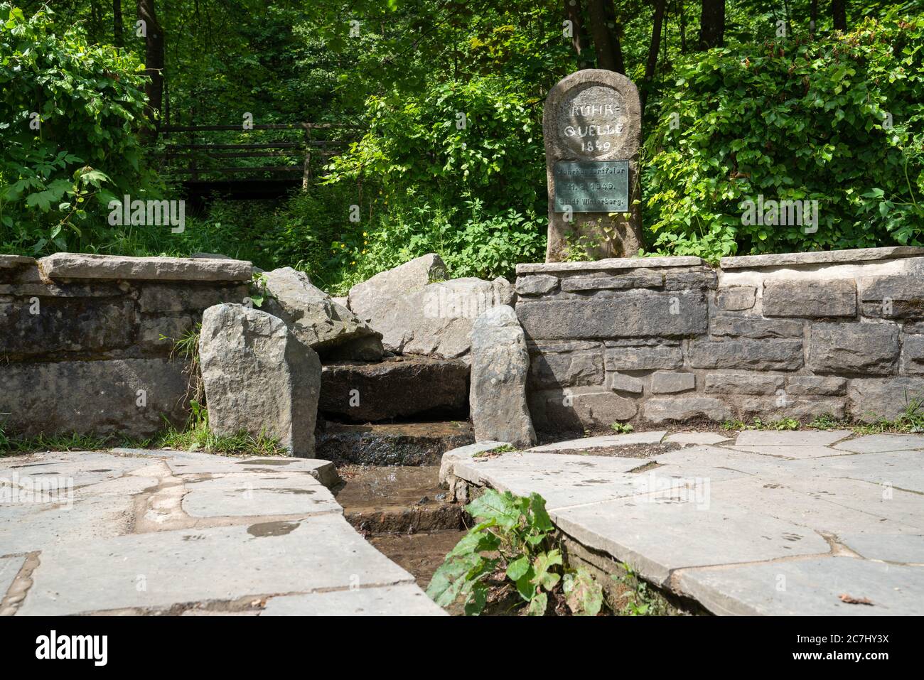 Spring of the river Ruhr with memorial stone and surrounded by trees ...