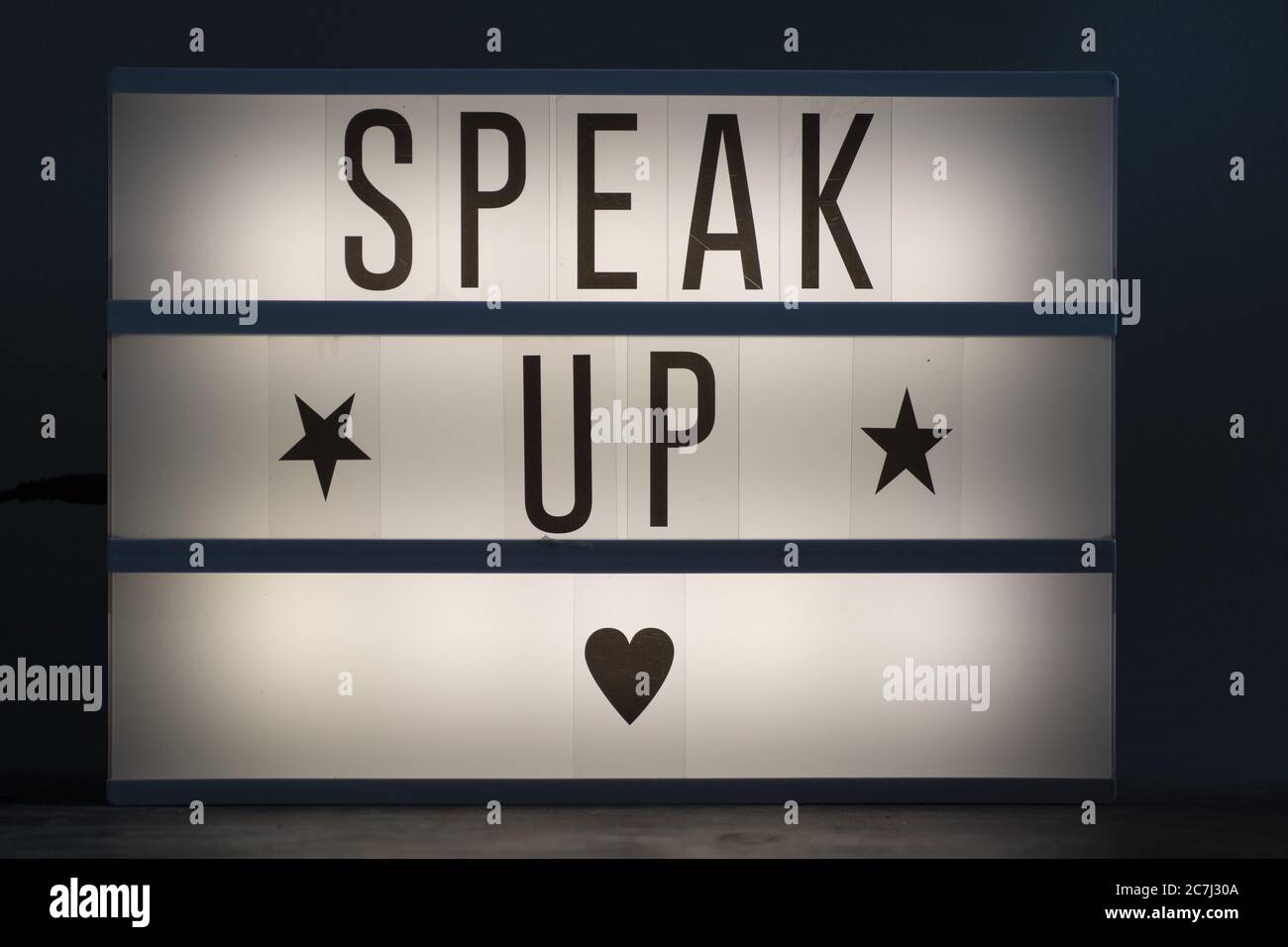 Speak up signage with stars and a heart on an illuminated whiteboard ...
