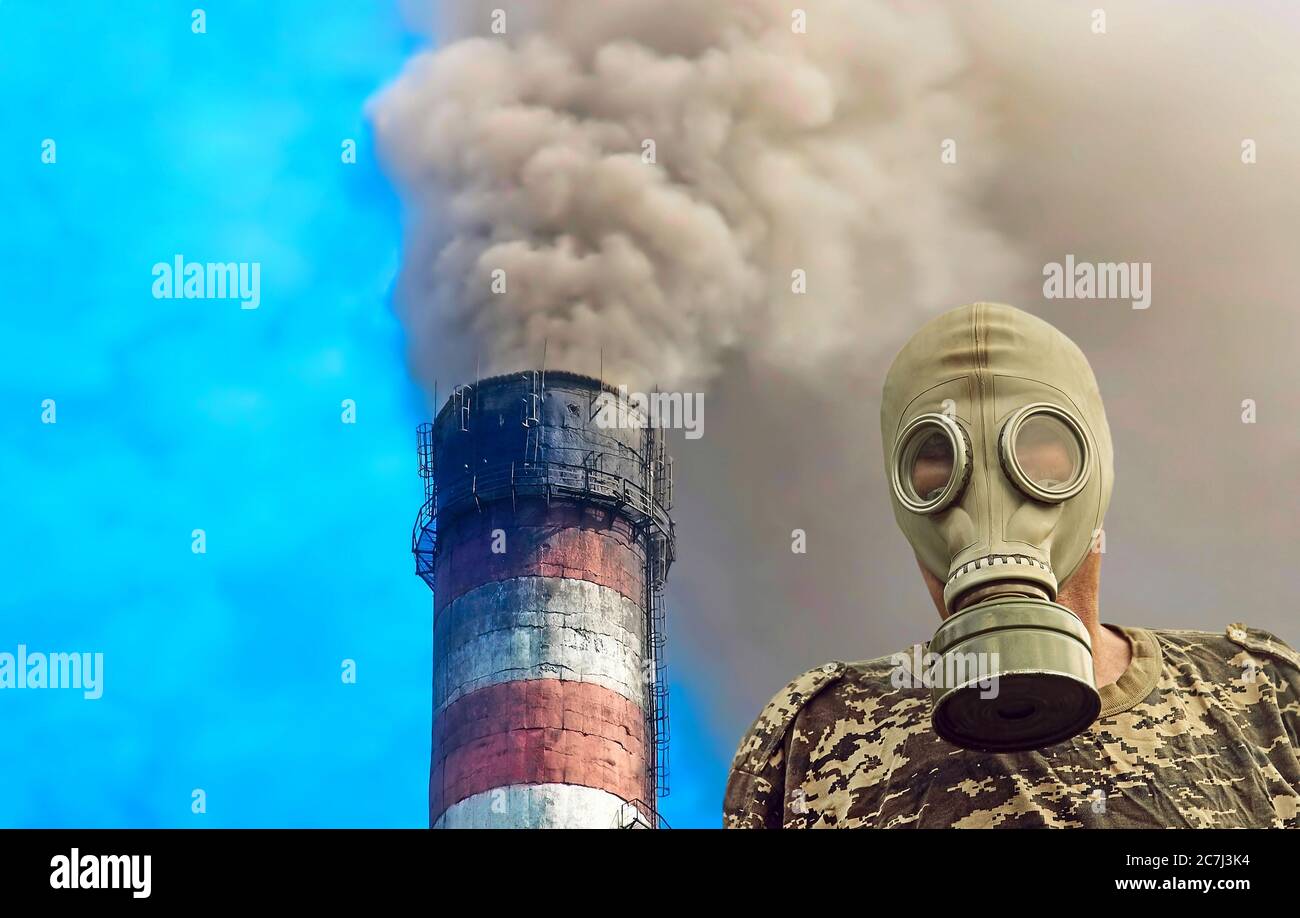 Men in gas mask taken closeup on industrial smoking pipe background ...