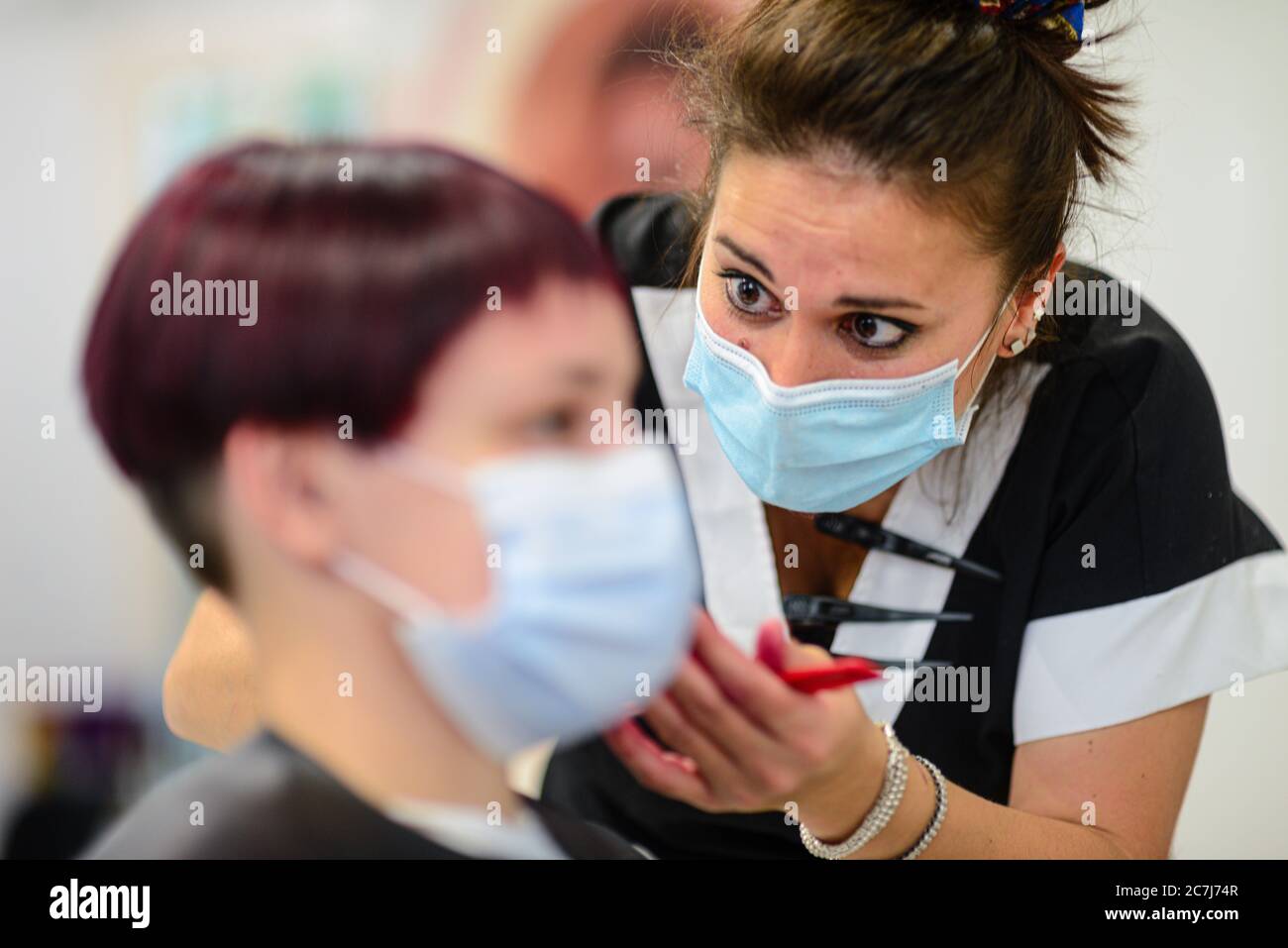 female professional hair stylist and young customer styling wearing a ...