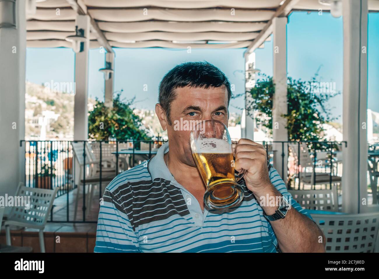 man drinks light beer sitting at a table in a cafe. Close up Stock ...