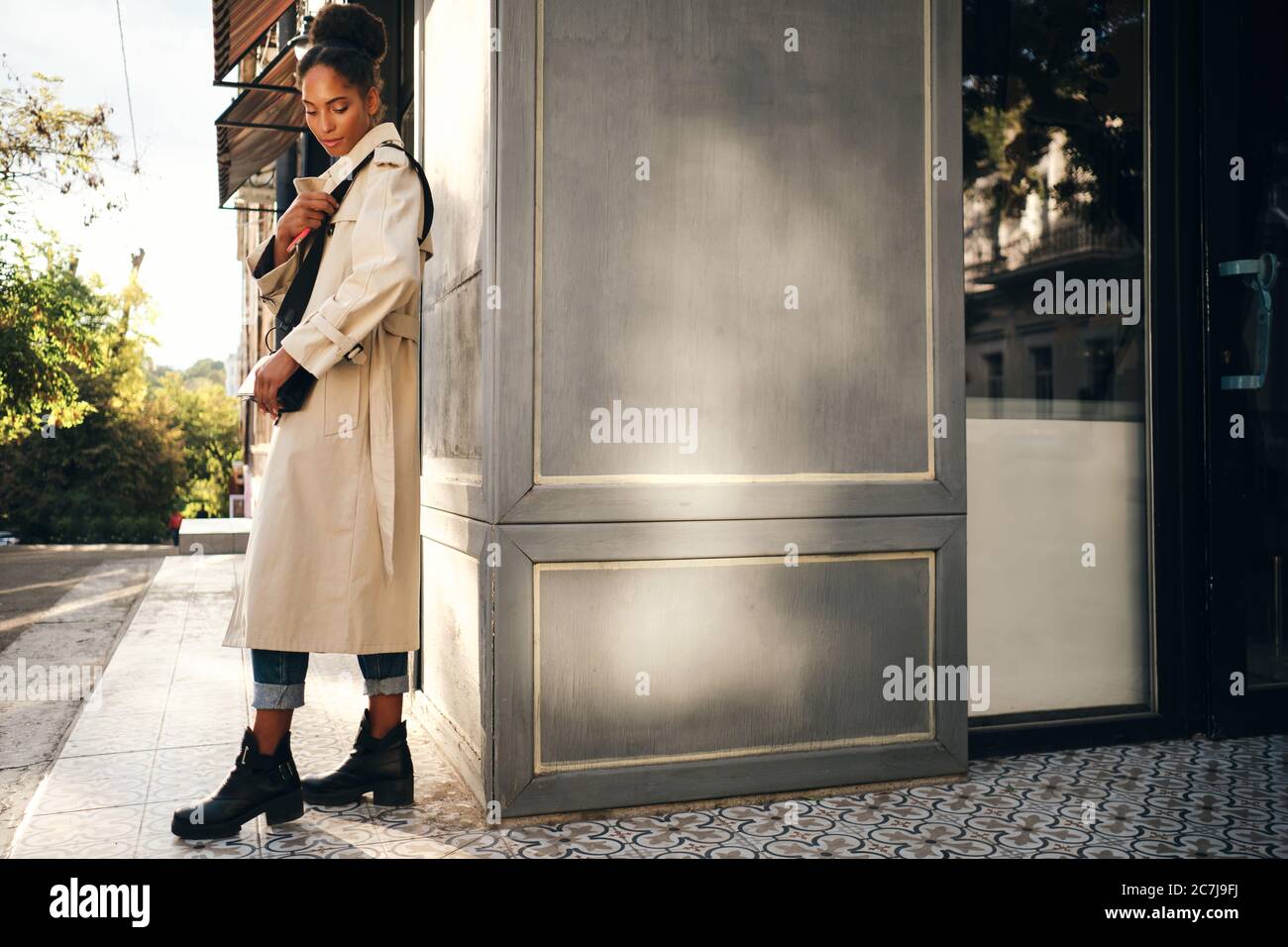 Side view of beautiful casual African American girl in trench coat with ...