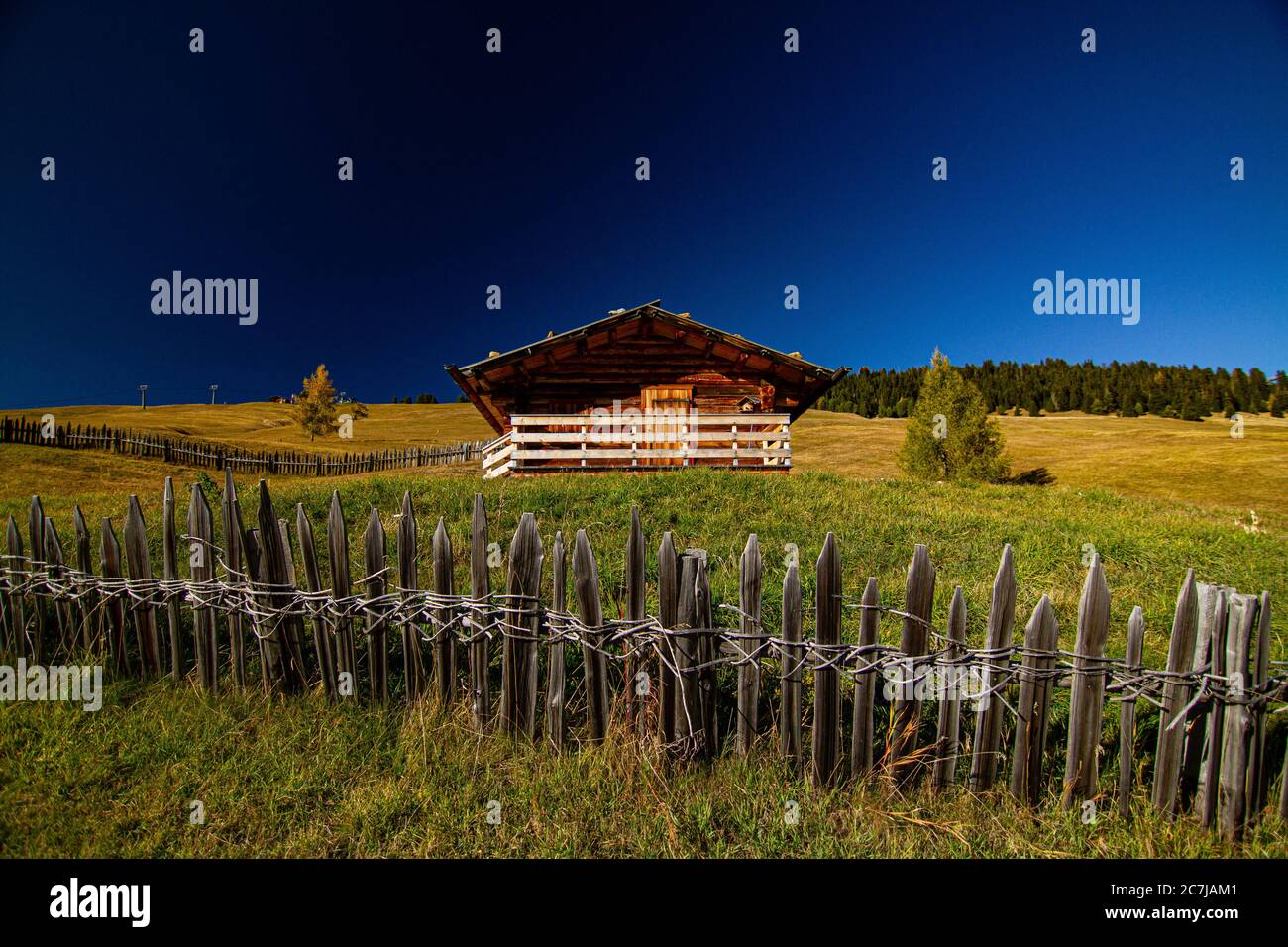 House in a grassy field with a wooden fence in dolomite Italy Stock ...
