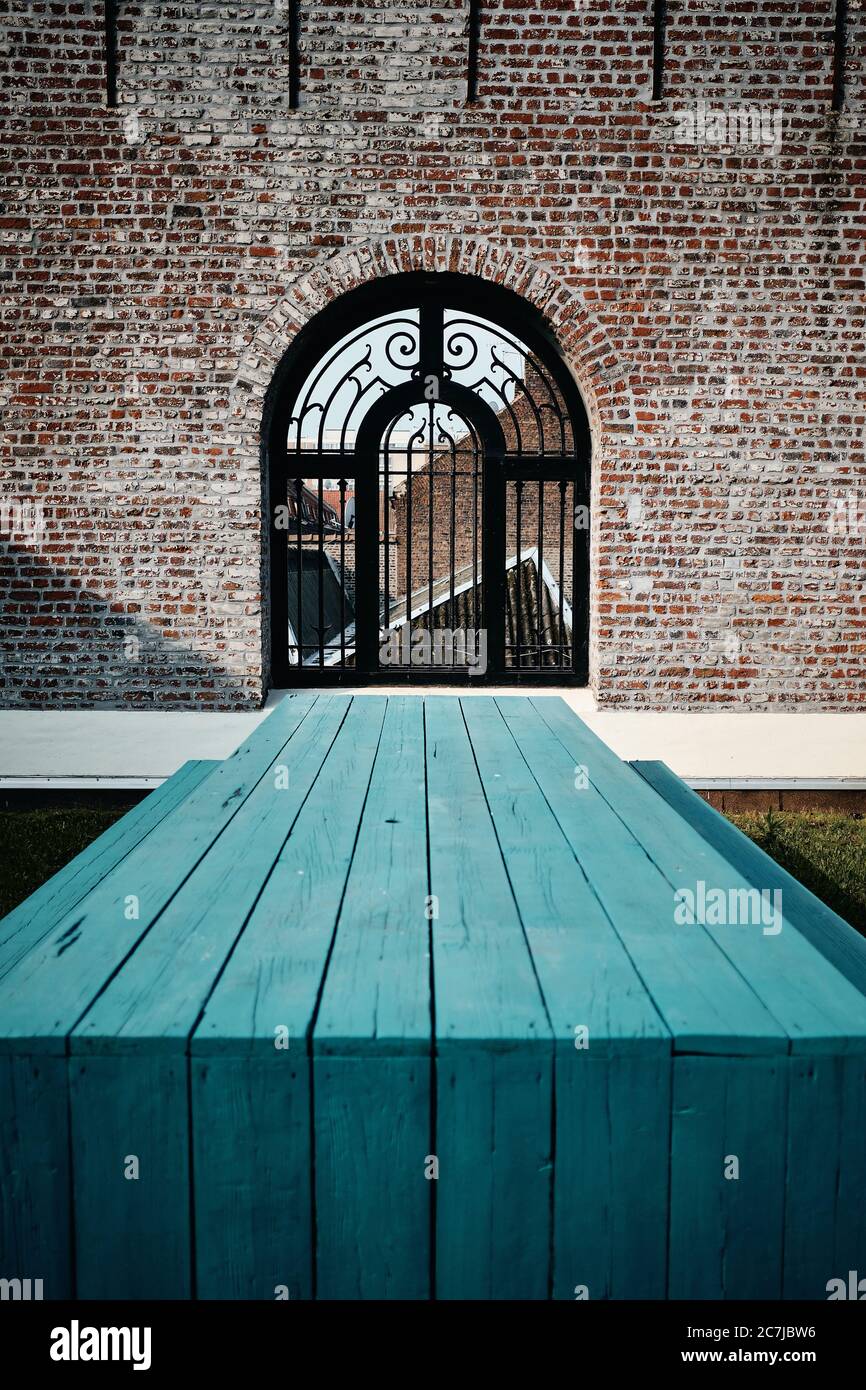 Vertical shot of a blue wooden bench in front of a building with an ...