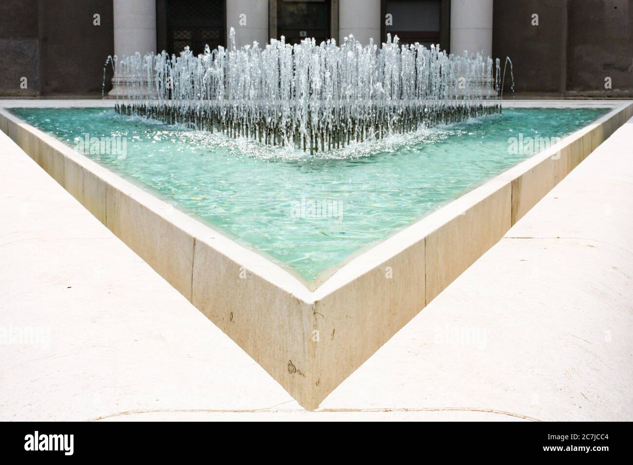 Triangle-shaped fountain surrounded by buildings under sunlight in ...