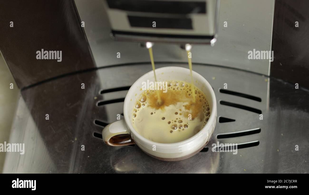 Espresso shot pouring out from coffee machine into small white and ...