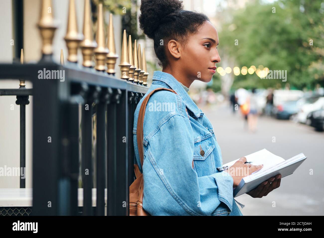 Side view of casual African American student girl in denim jacket with ...