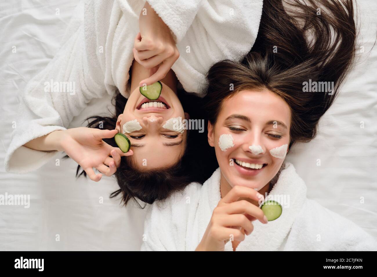 Two Young Attractive Women With Dark Hair In White Bathrobes Lying In