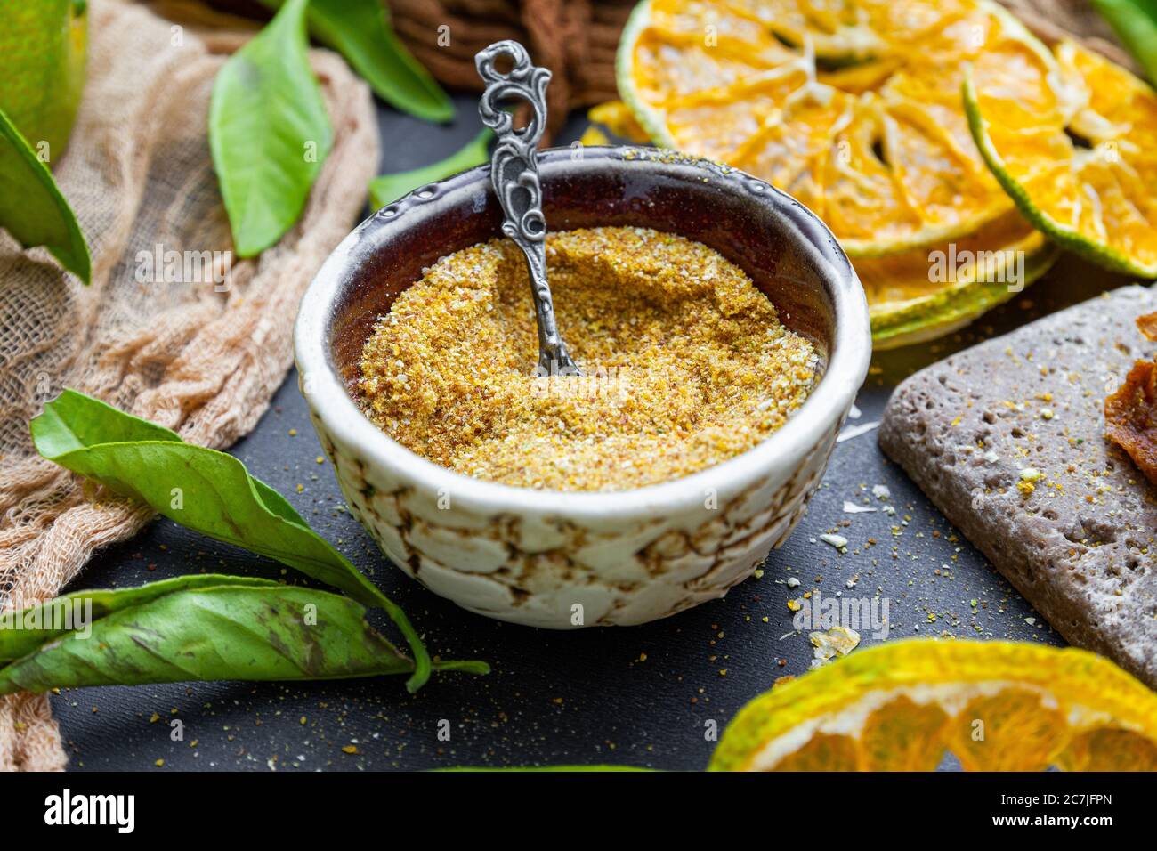 Closeup of tangerine powder in a bowl on a table surrounded by dry ...