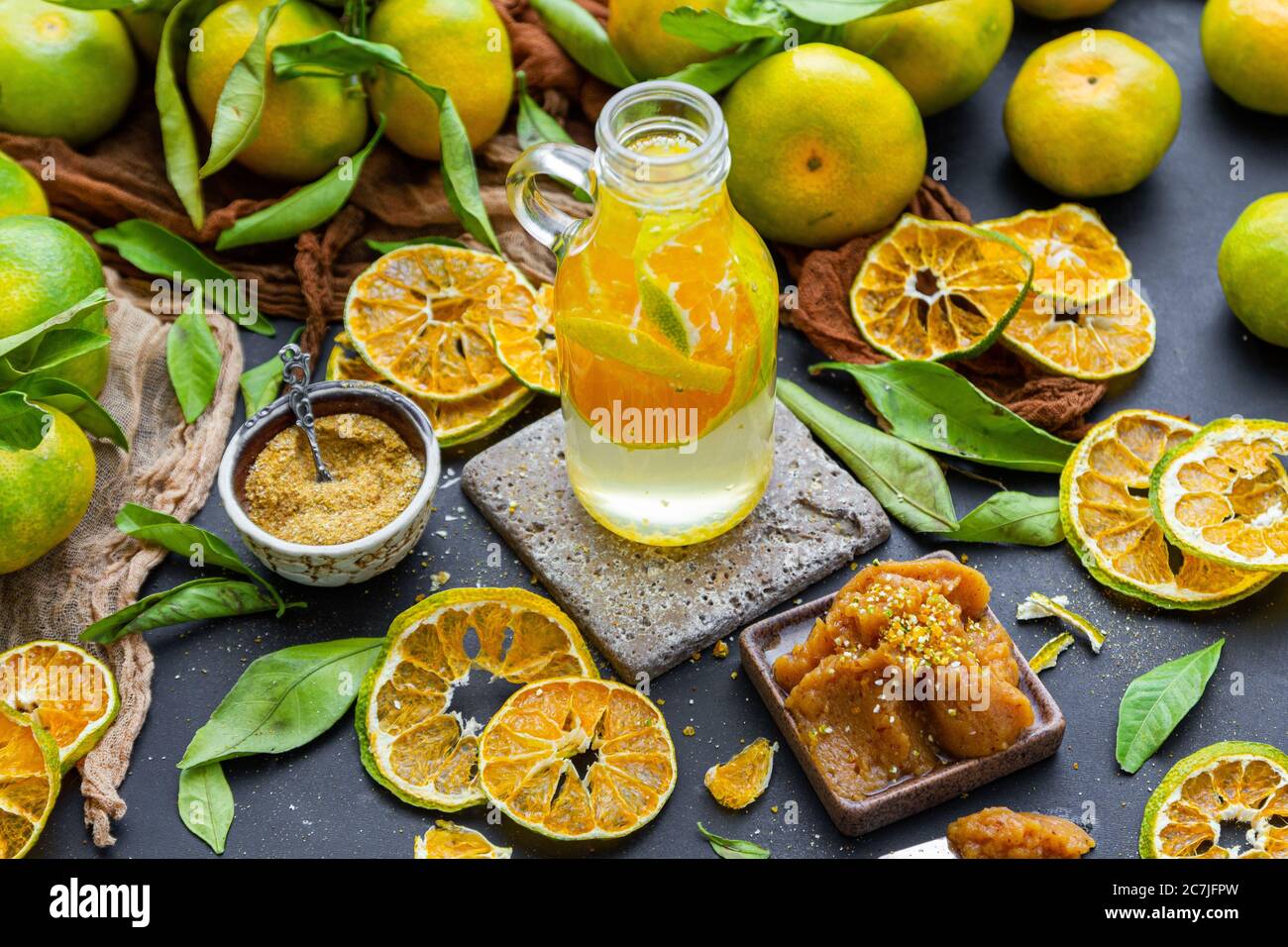Bottle of mandarine water on a table surrounded by dry citruses ...