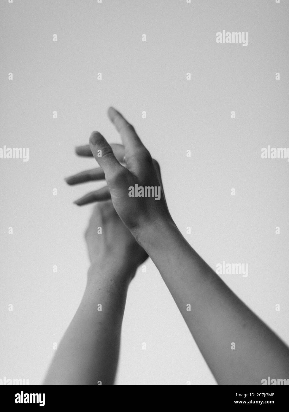 Greyscale of human hands under the lights against a white background ...