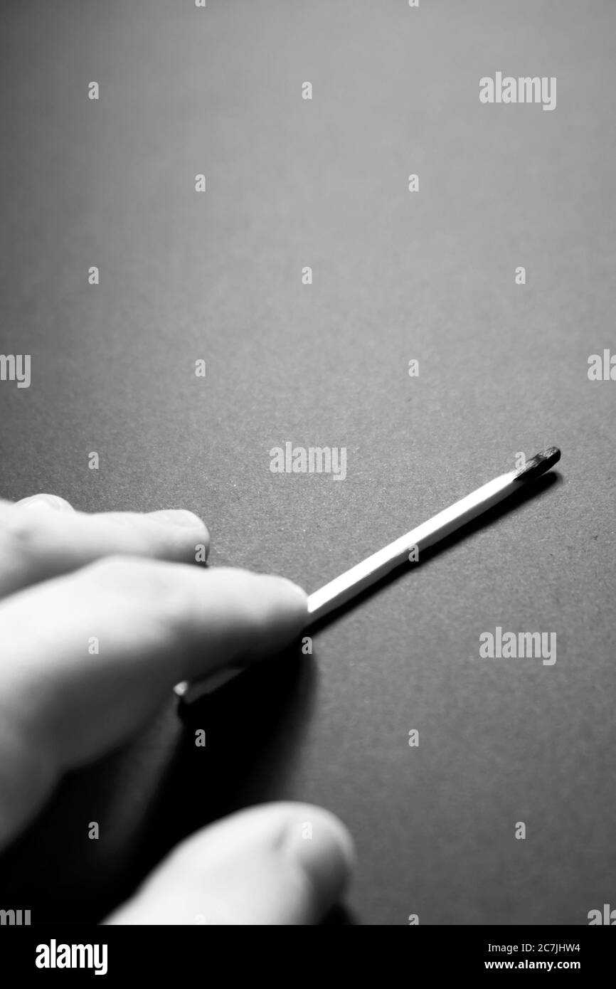 Vertical grey scale shot of a person putting his hand on a burnt ...