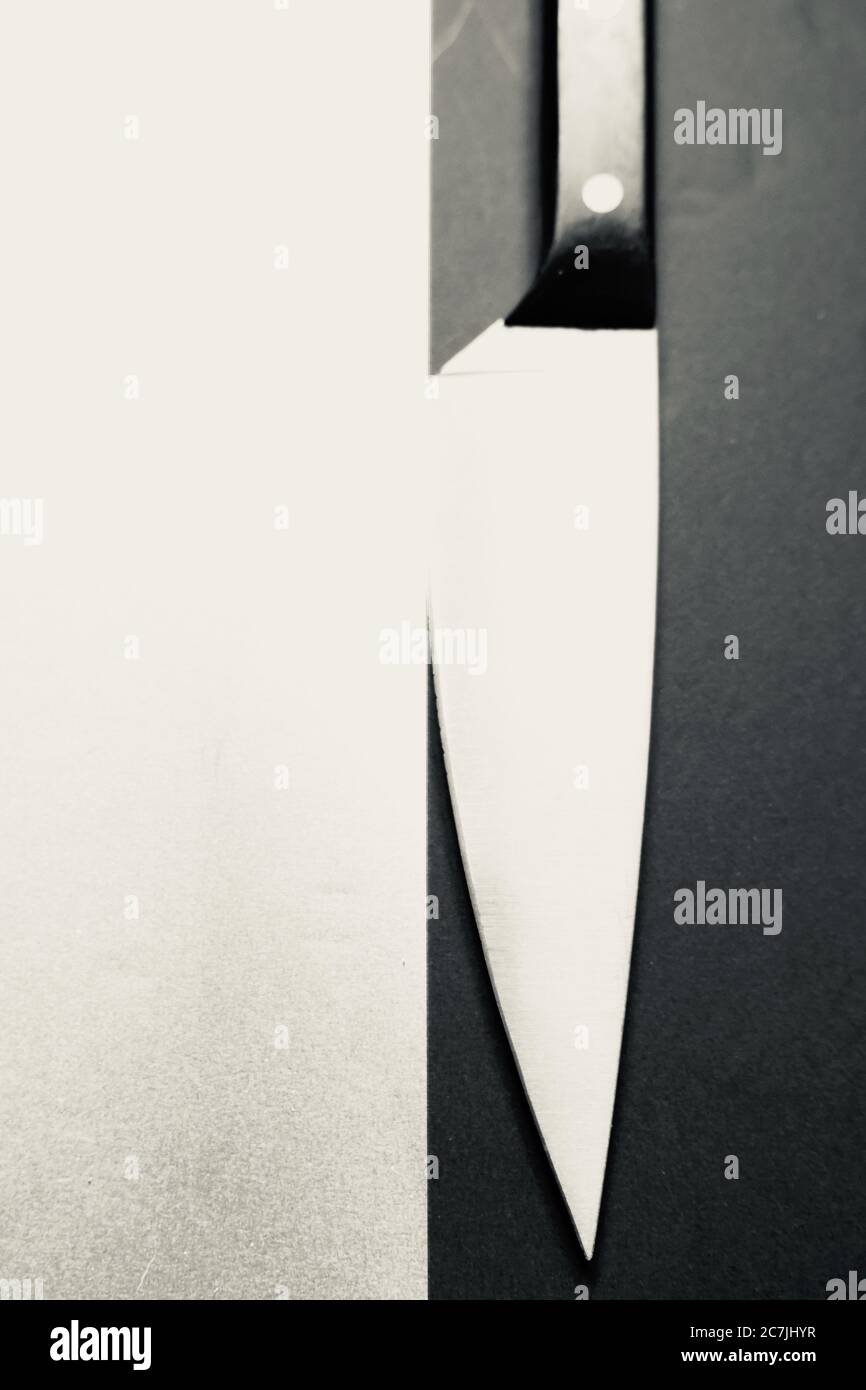 Vertical grey scale shot of a knife on a black and white surface ...