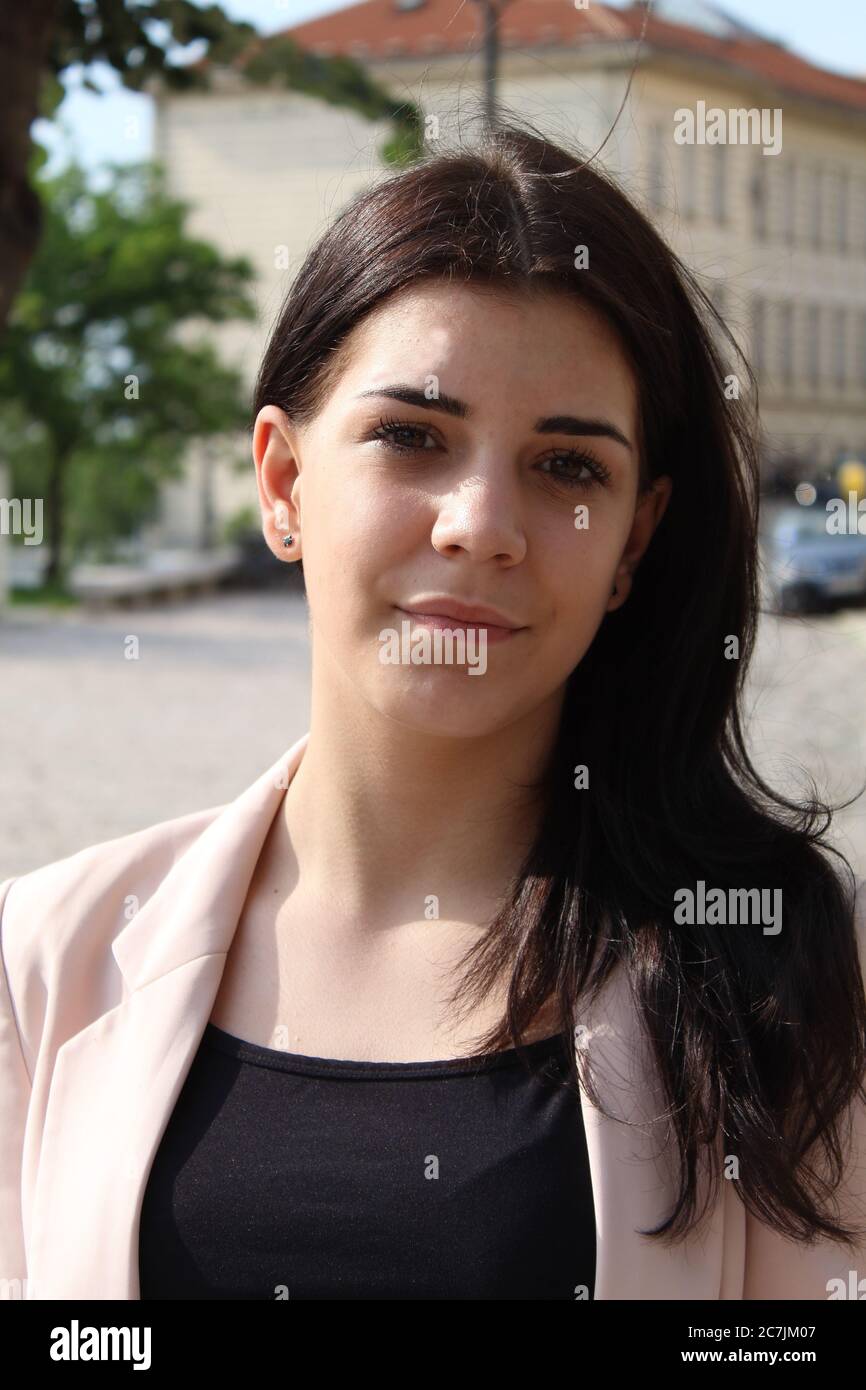 Portrait Of Young Black Haired Girl On Street In Old Part Of Town Stock