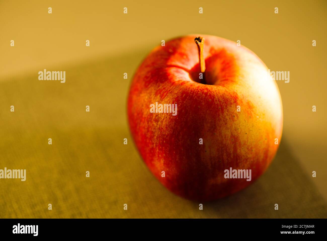 Closeup of a red apple reflecting on the table under the lights with a ...
