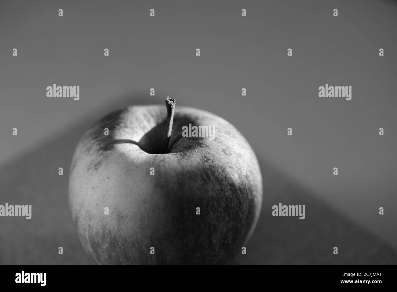 Greyscale of an apple reflecting on the table with a blurry background ...