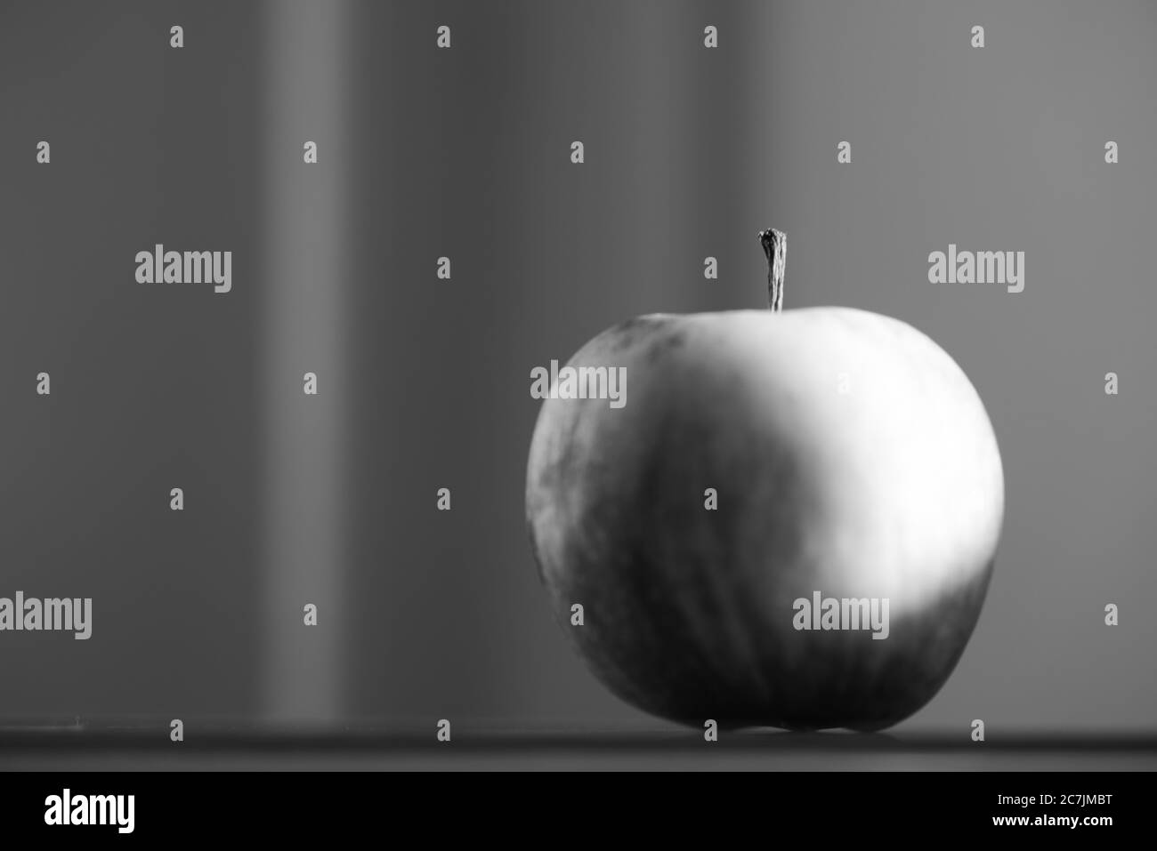Greyscale of an apple reflecting on the table with a blurry background ...