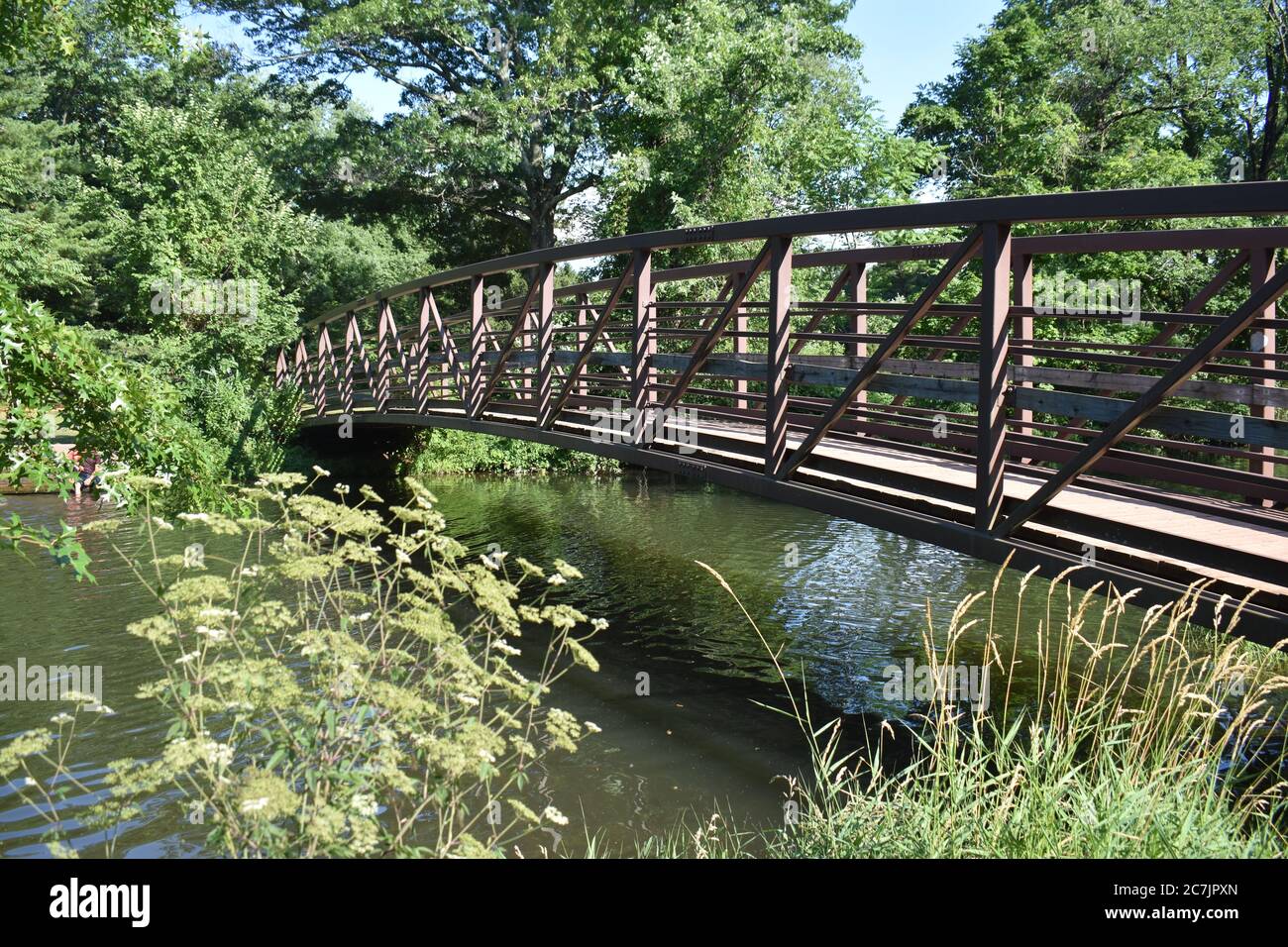 Steel pedestrian footbridge with wooden walkway crossing a narrow ...