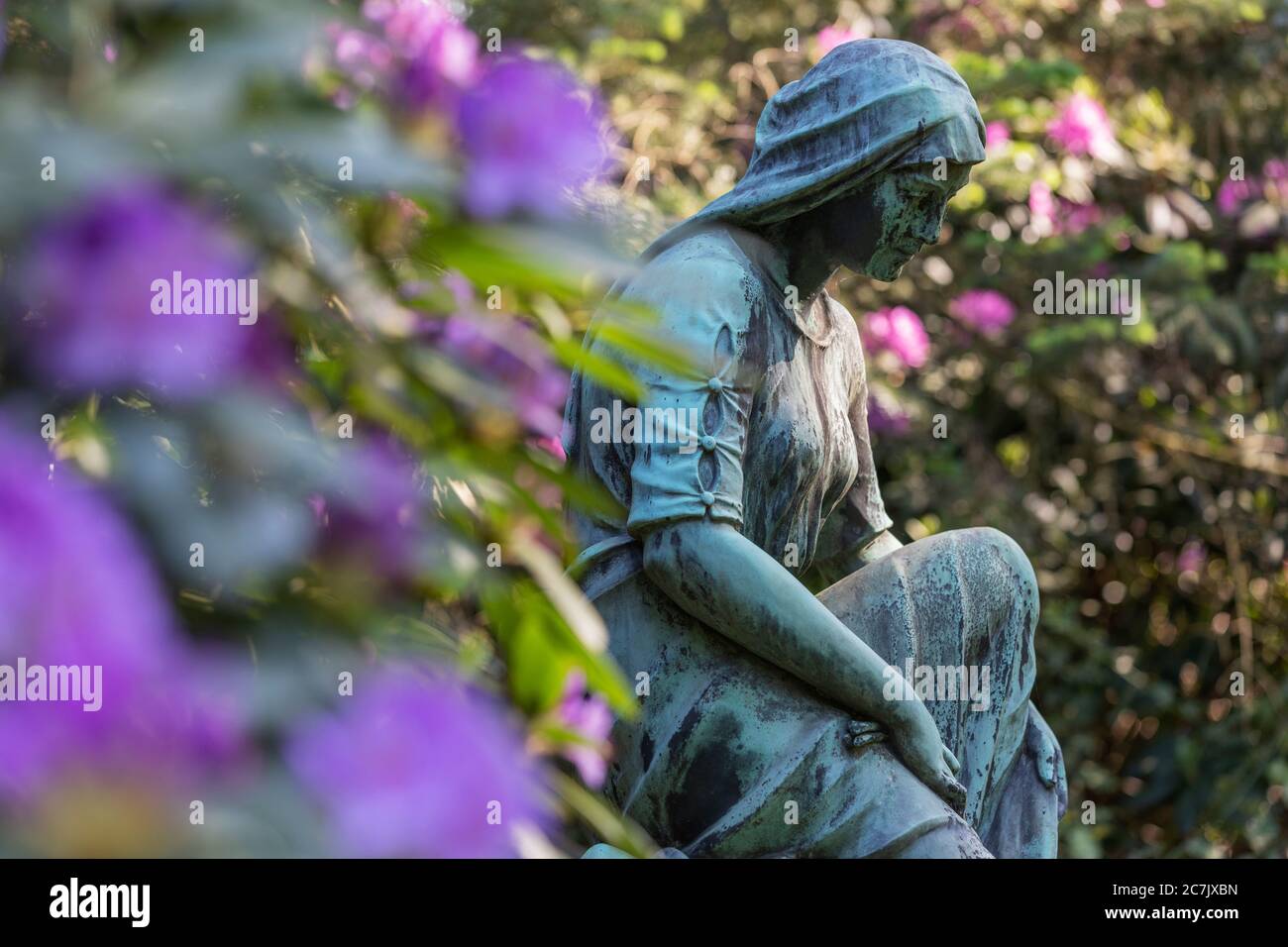 Mourning woman statue, rhododendron blossom, Ohlsdorf cemetery, Hamburg ...