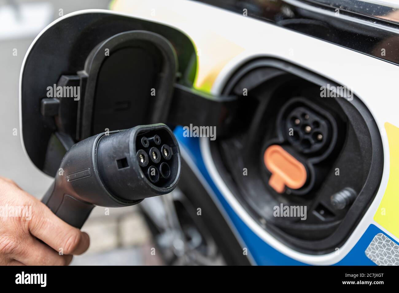 Hand holds charging plug, police electric car, detail, loading flap ...