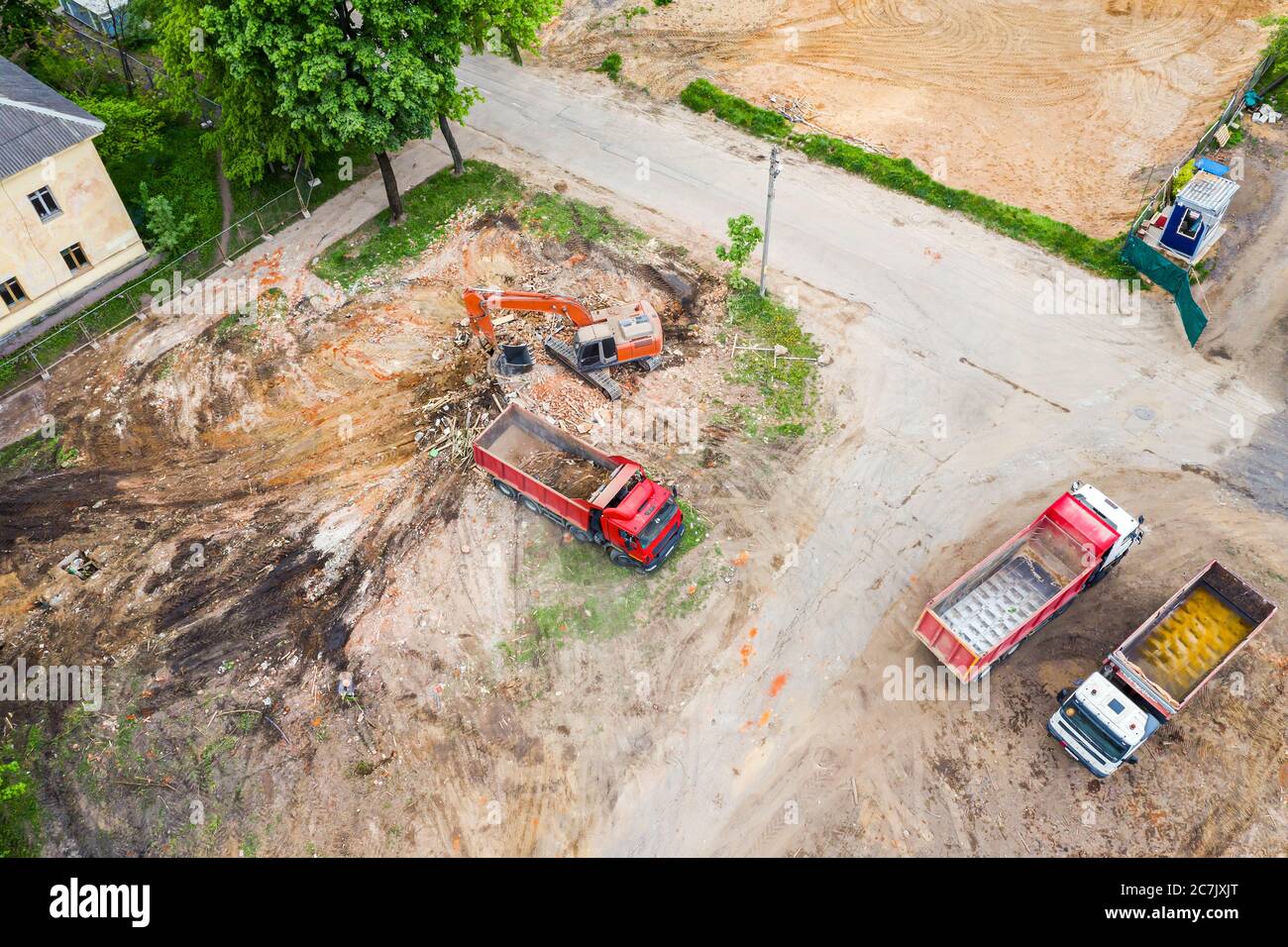 excavator and dump trucks working at the demolition site in ruins ...