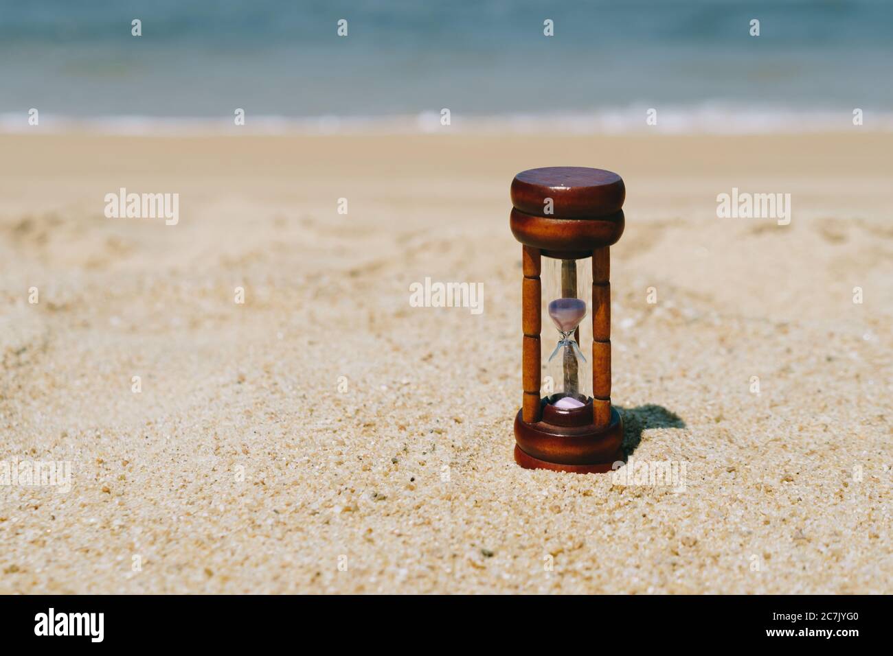 Small hourglass show time is flowing on sand beach texture background ...