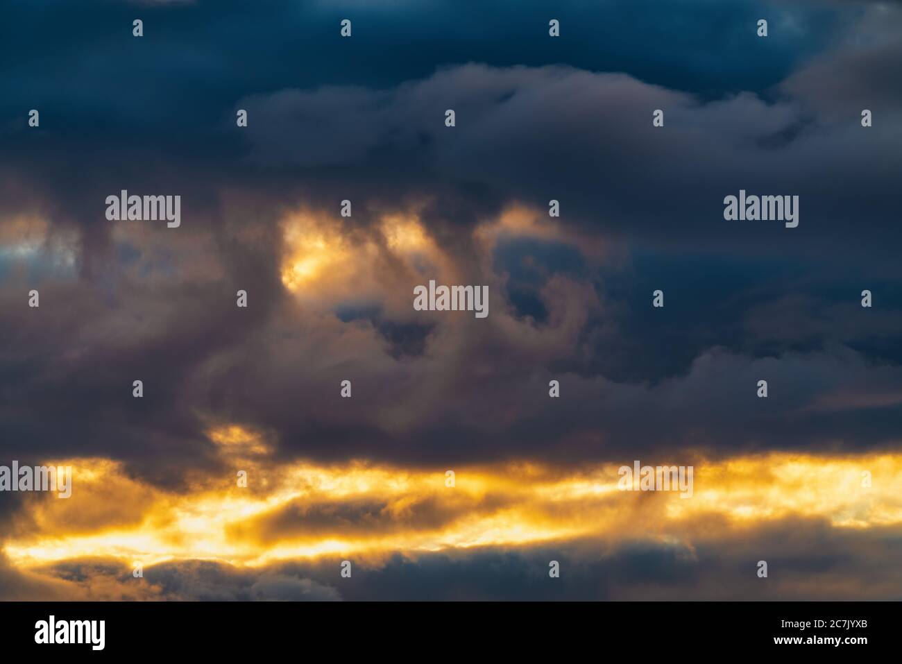Impressive clouds in sky illuminated by rays of sun at sunset to change ...