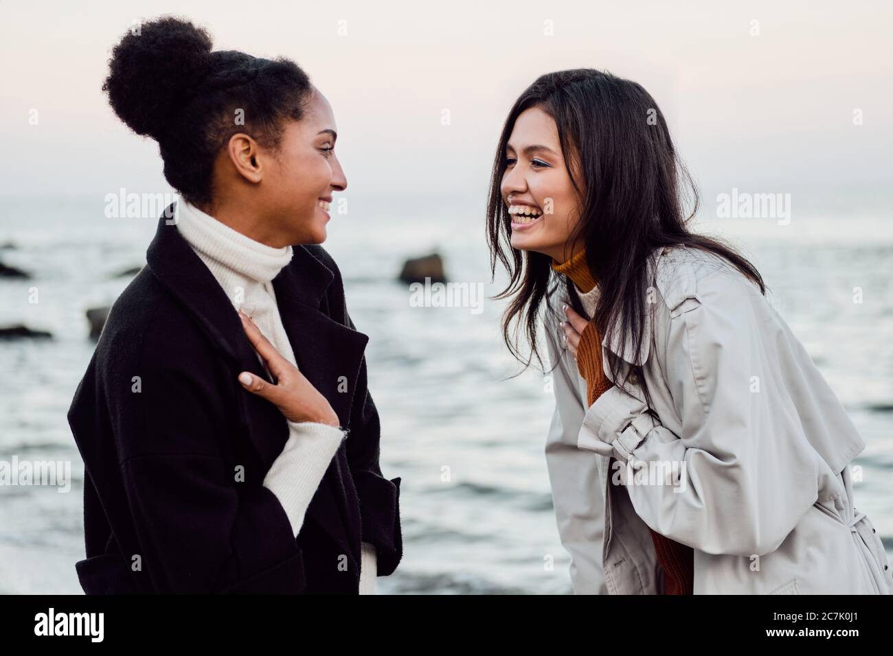 Two cheerful girls happily talking walking together by the sea Stock ...