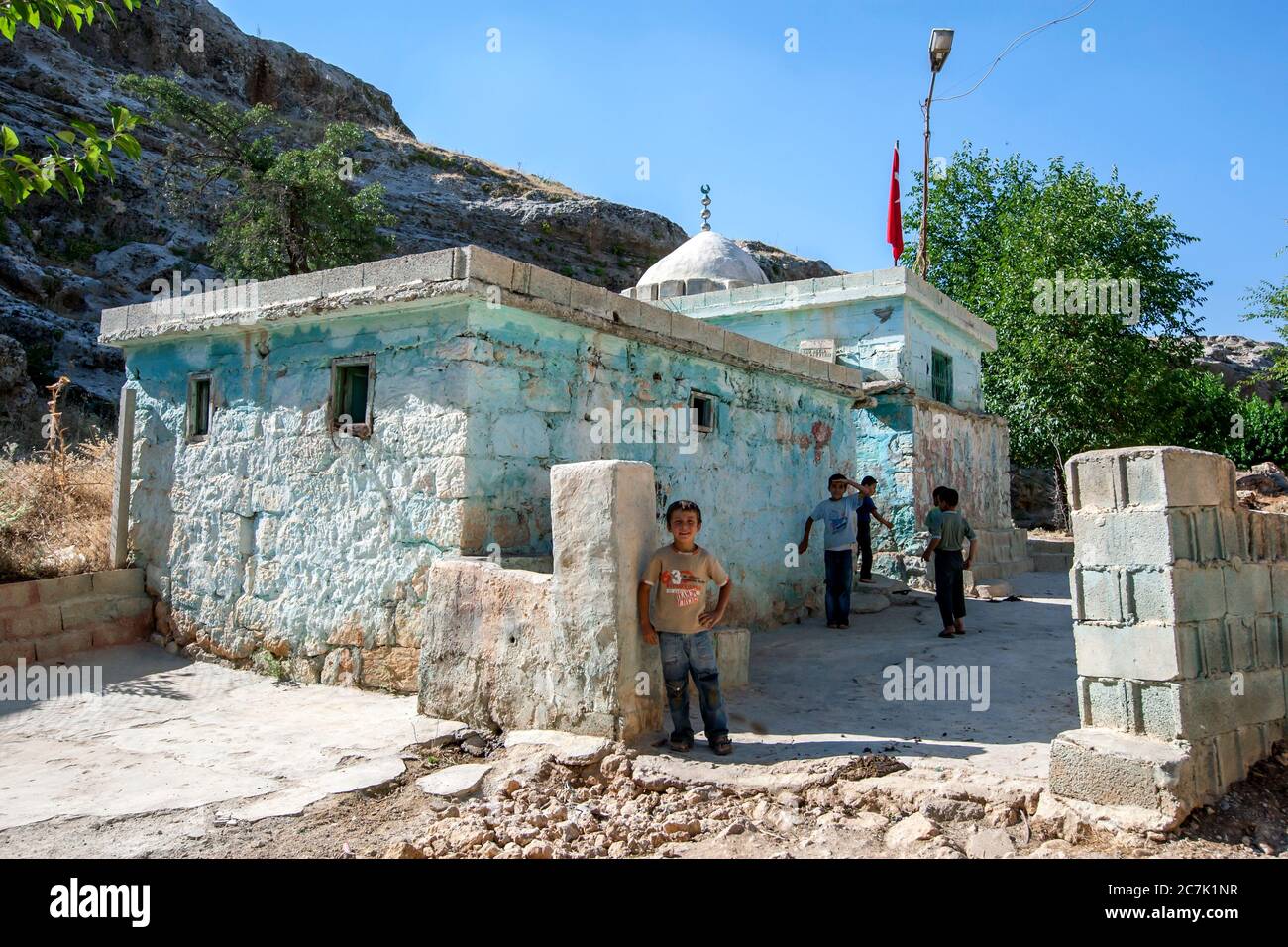 Kurdish boys stand outside a burial tomb in a small rural village near ...
