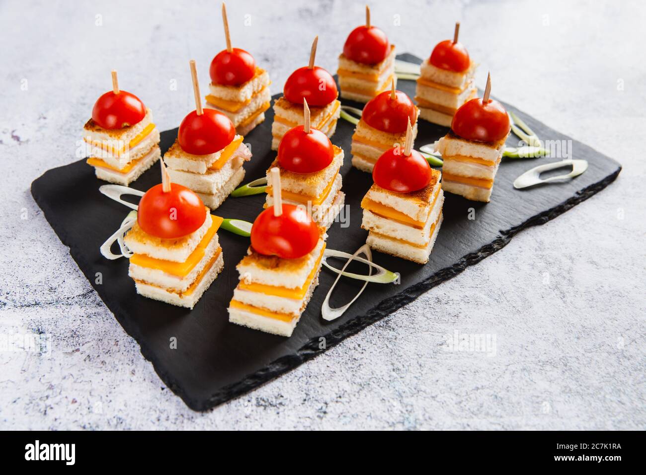 Cheese canapes decorated tomato on black plate Stock Photo - Alamy