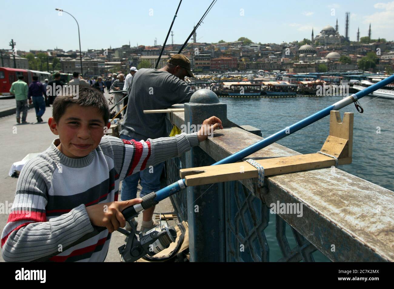 A young Turkish fisherman on Galata Bridge at Istanbul in Turkey. He is ...
