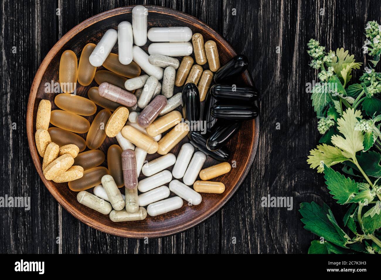 Multivitamin pills on a clay plate, on a vintage wooden table, with a ...