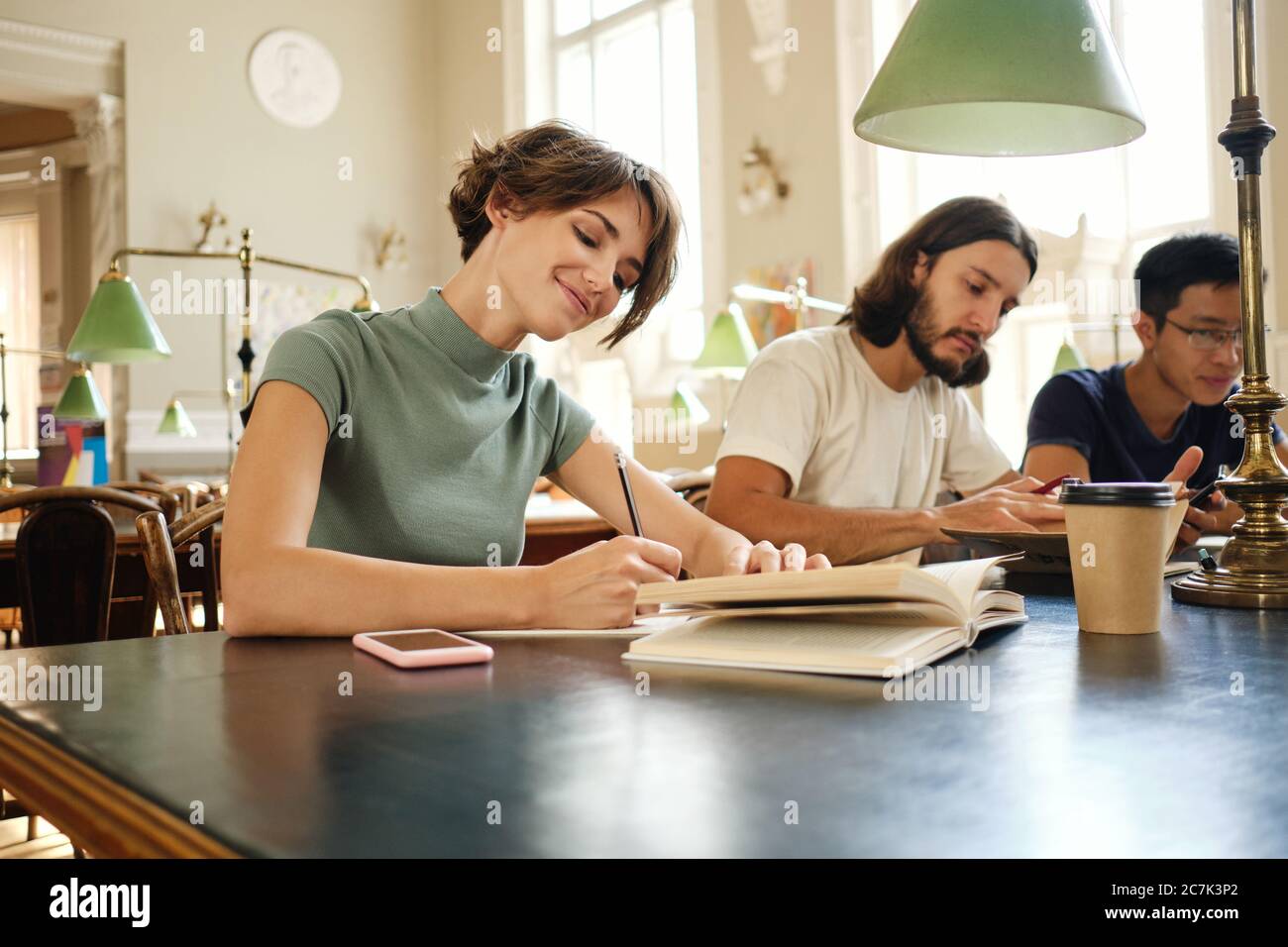 Young attractive female student with book happily working on study ...