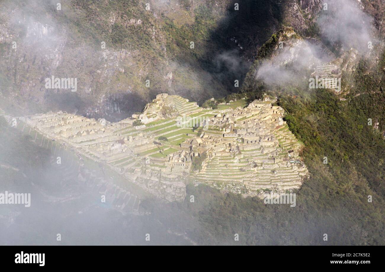 Machu Picchu citadel through clouds in the morning, seen from Sun Gate ...