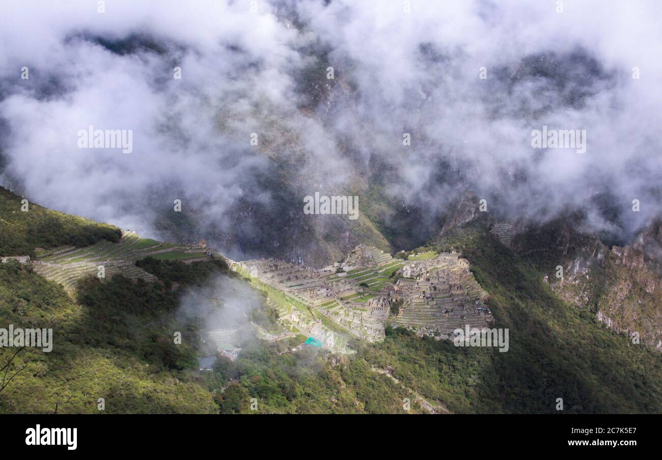 Machu Picchu citadel through clouds in the morning, seen from Sun Gate ...