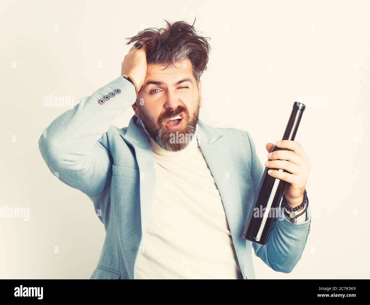 Stylish handsome man in blue suit drinking from bottle over white ...