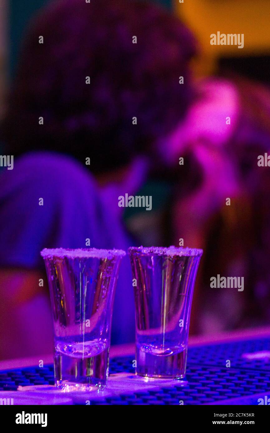 Tequila shots on the bar table at night party, people on the background ...