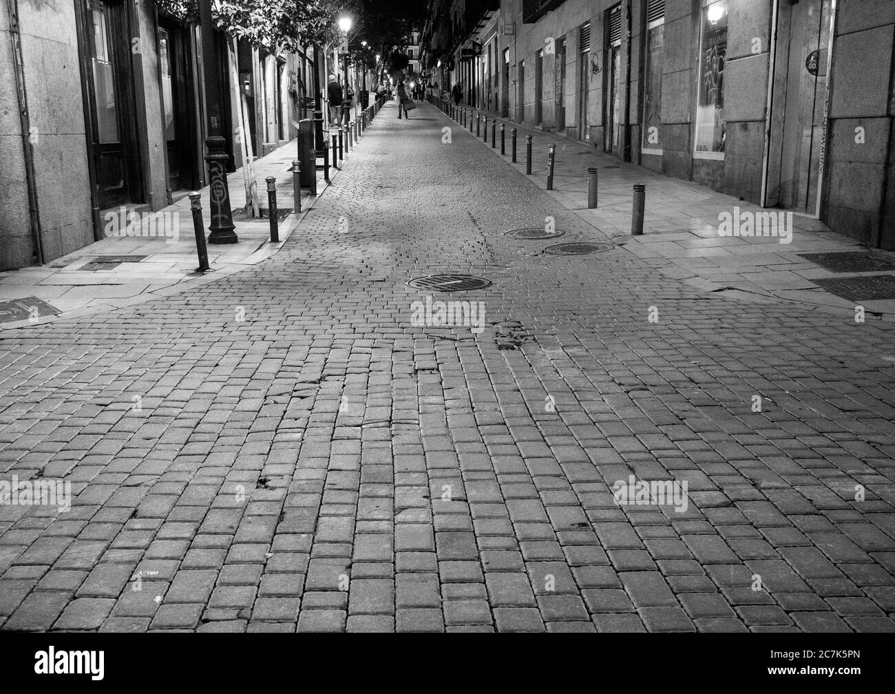 Greyscale of a narrow road surrounded by buildings and lights during ...