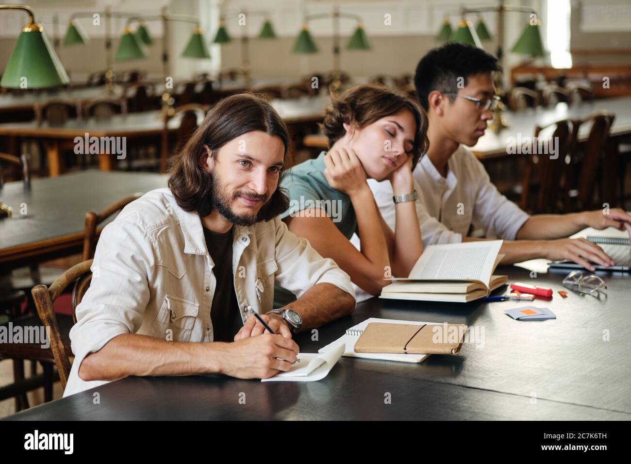 Group of young multinational students studying together in library of ...