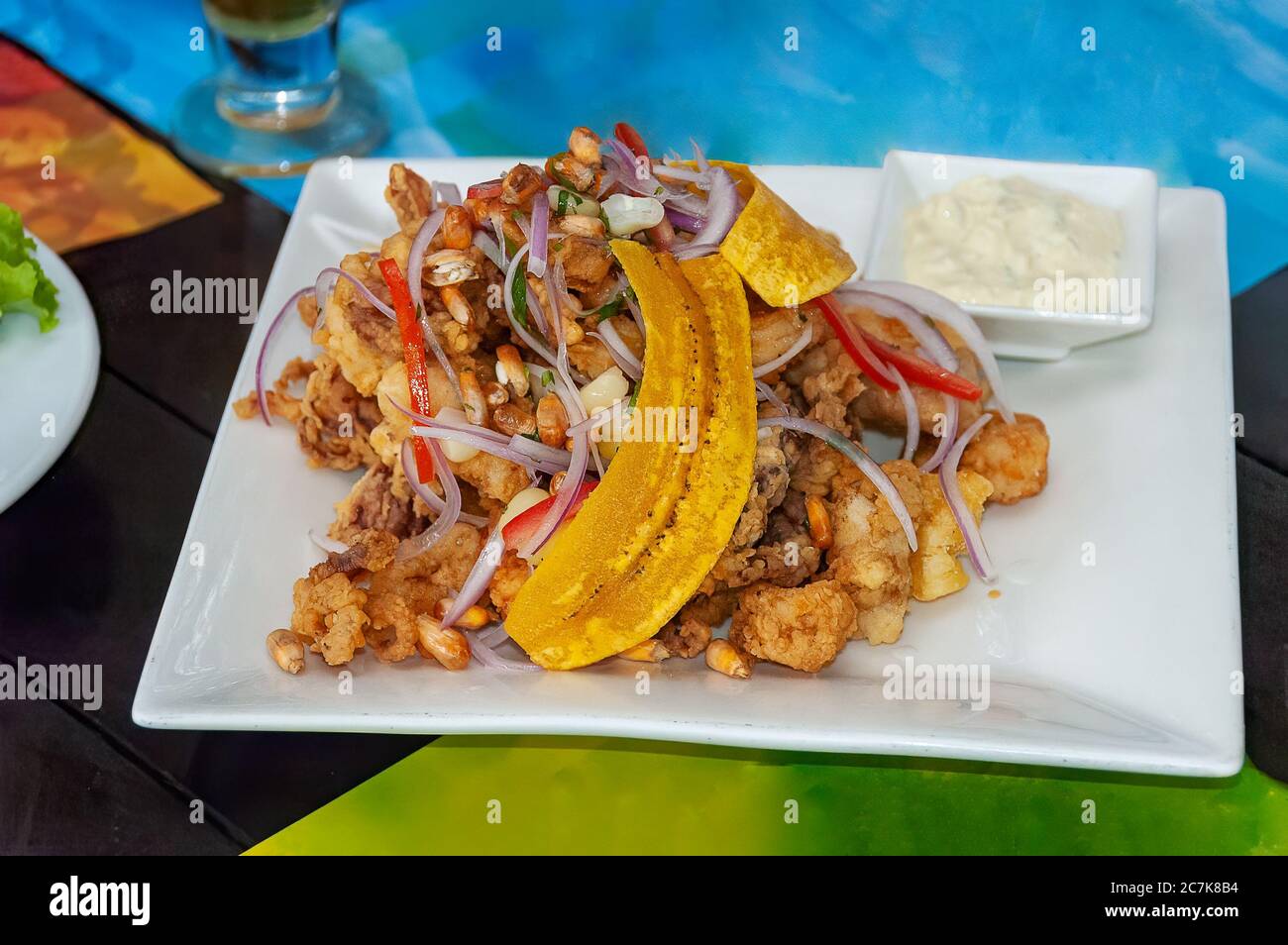 A popular Peruvian dish of mixed fried seafood topped with large corn ...