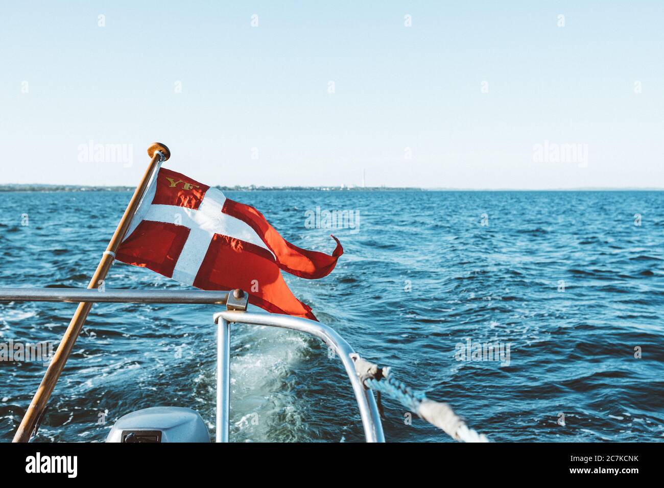 And white flag on a boat floating on top of the ocean under a blue sky ...